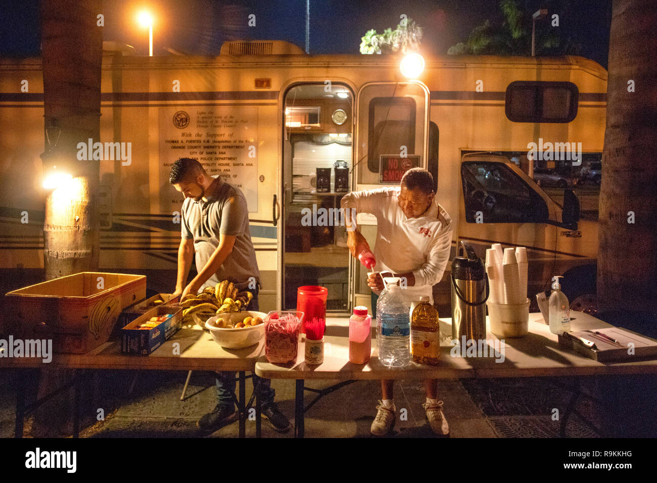Outside a specialized van, Caucasian and Hispanic volunteers prepare ...