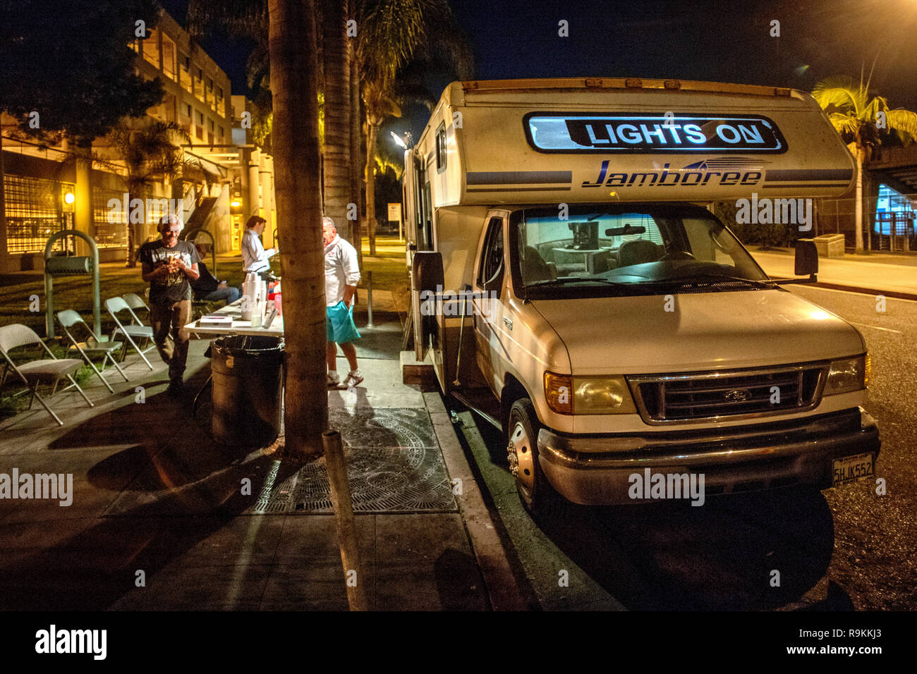 Outside a specialized van, Caucasian and Hispanic volunteers serve free ...
