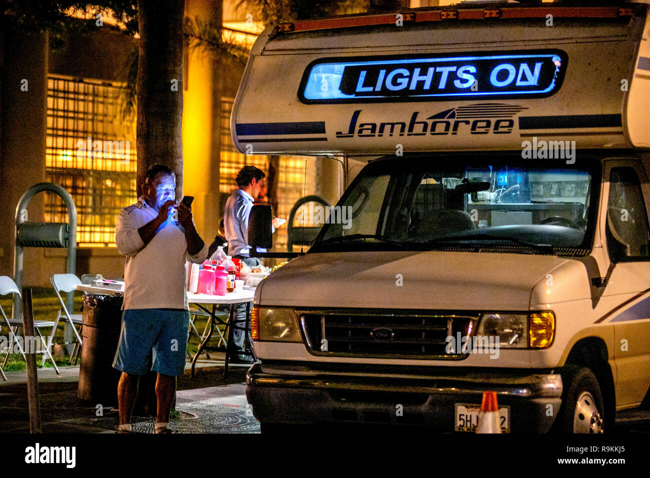 Outside a specialized van, Caucasian and Hispanic volunteers serve free ...