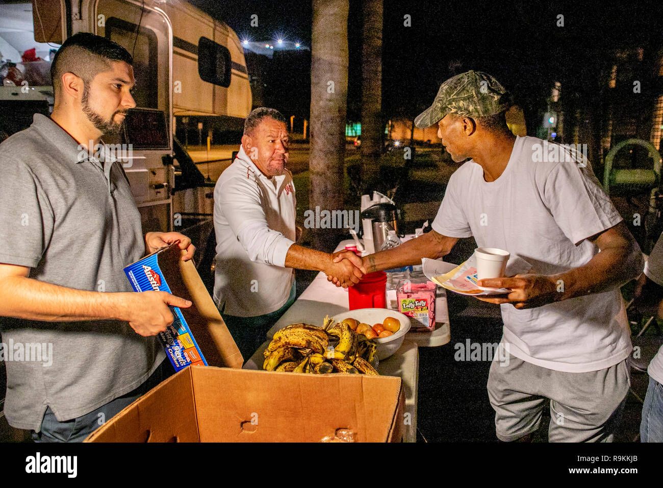Outside a specialized van, Caucasian and Hispanic volunteers serve free ...