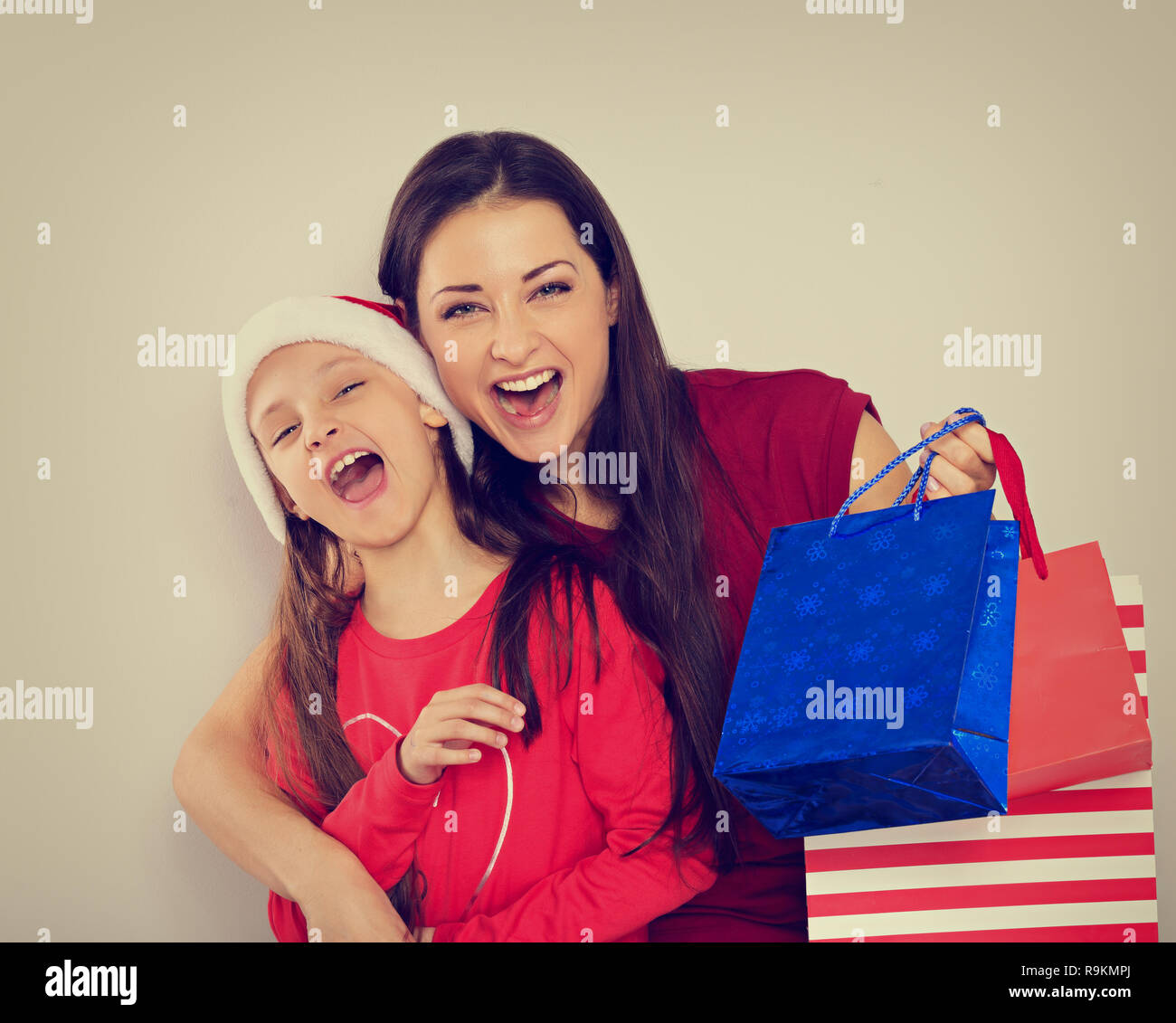 Happy laughing mother with open mouth hugging with love her cute joying ...