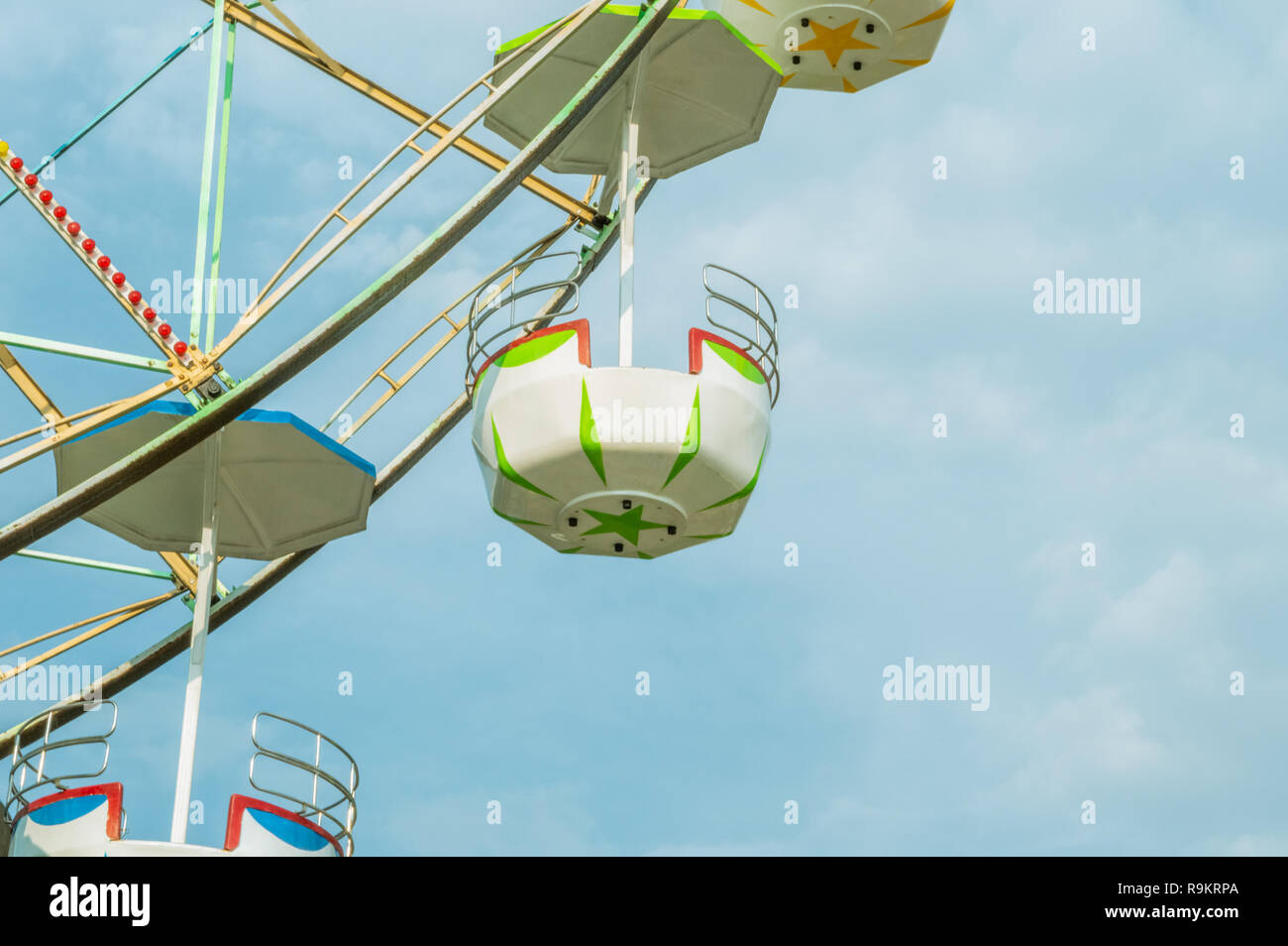 Low angle view of a big wheel with colorful cabins over sky background ...