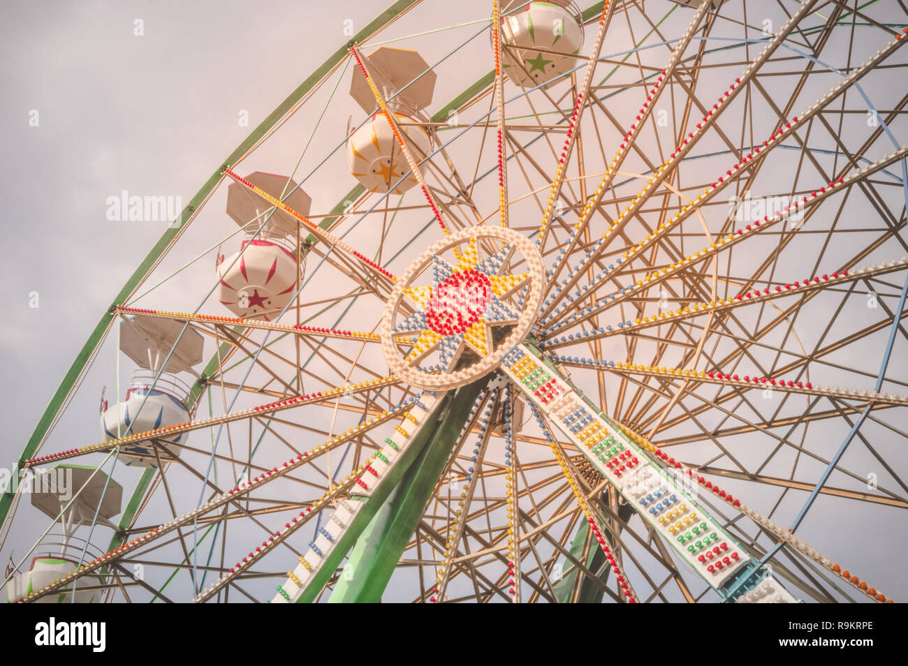 Low angle view of a big wheel with colorful cabins over sky background ...