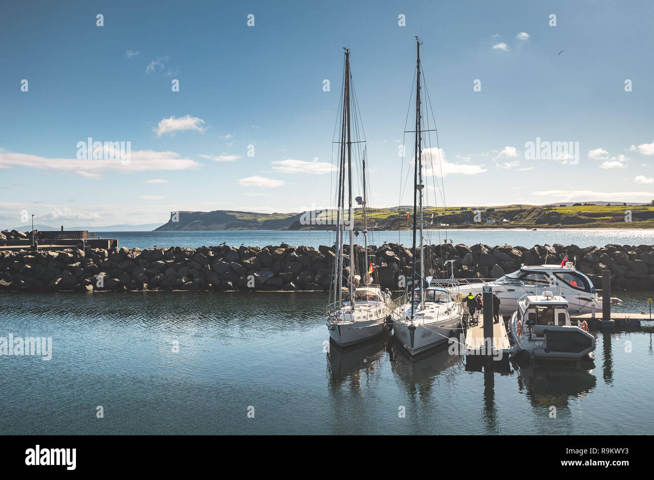 Touristic yachts, boat next to the small pier and stone fence. Northern ...