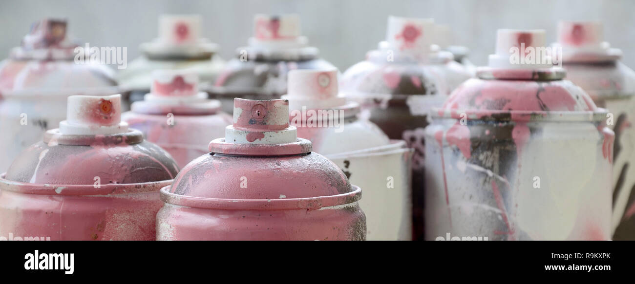 A lot of dirty and used aerosol cans of bright pink paint. Macro ...