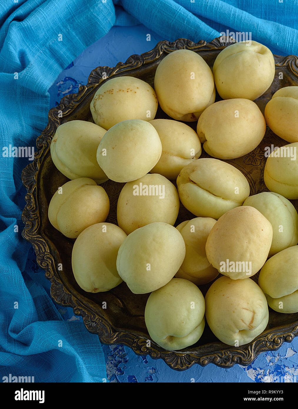 ripe apricots in a copper iron plate on a blue background, top view ...
