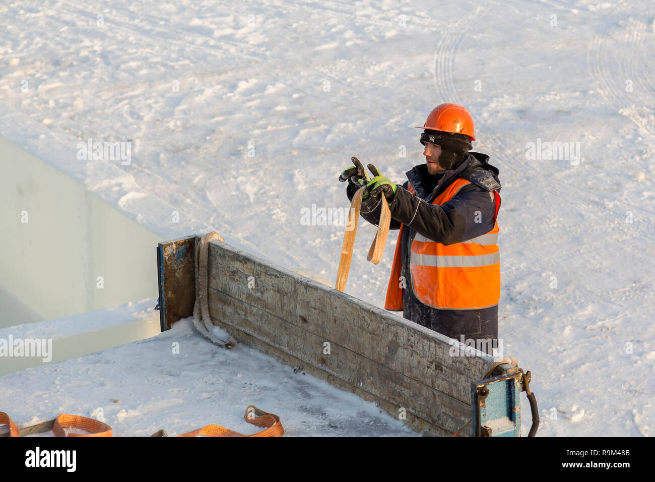 The slinger in the vest and orange helmet guides the movement of the ...