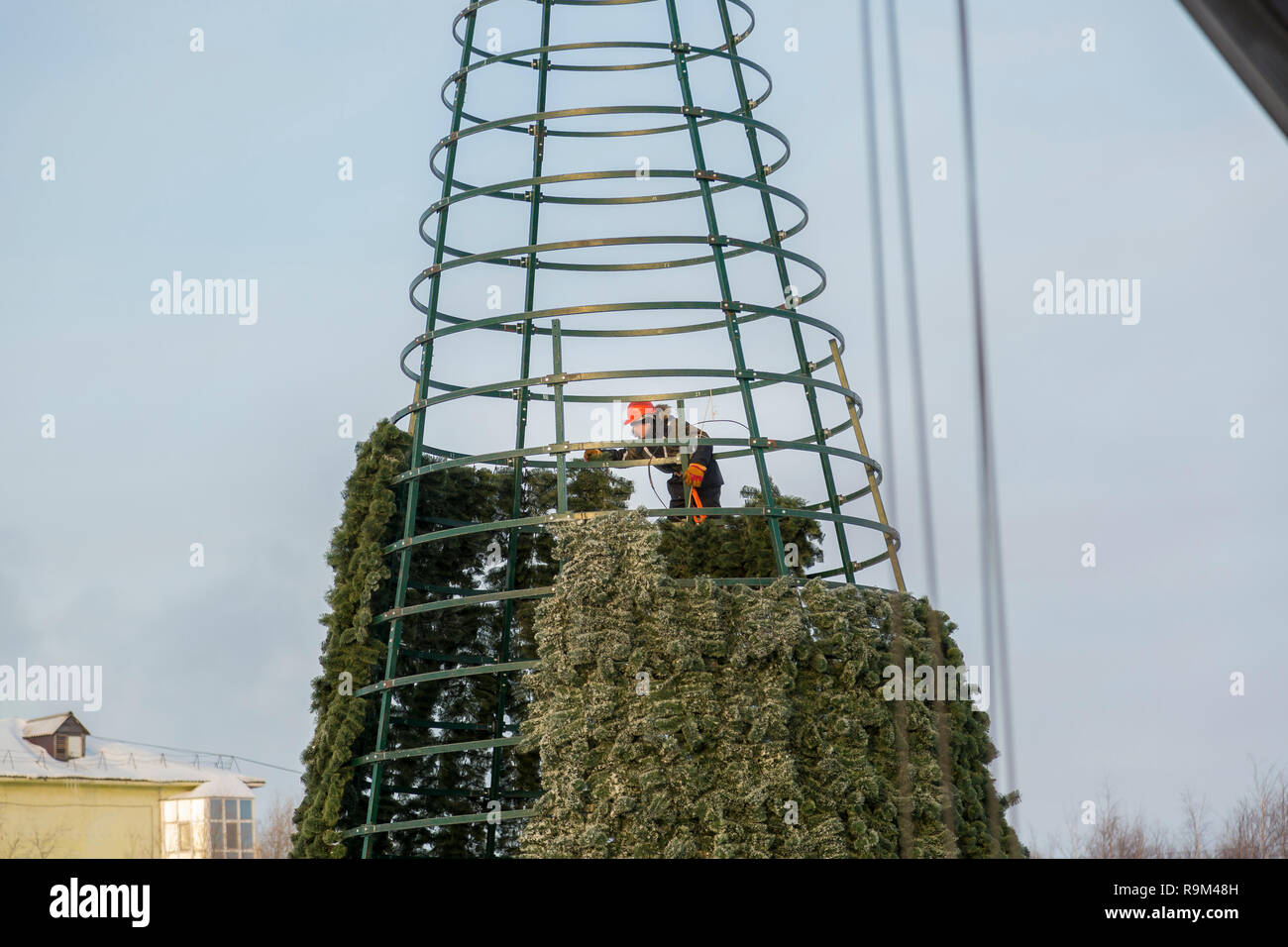 Fitter in a jacket and helmet at the installation of the Christmas tree ...