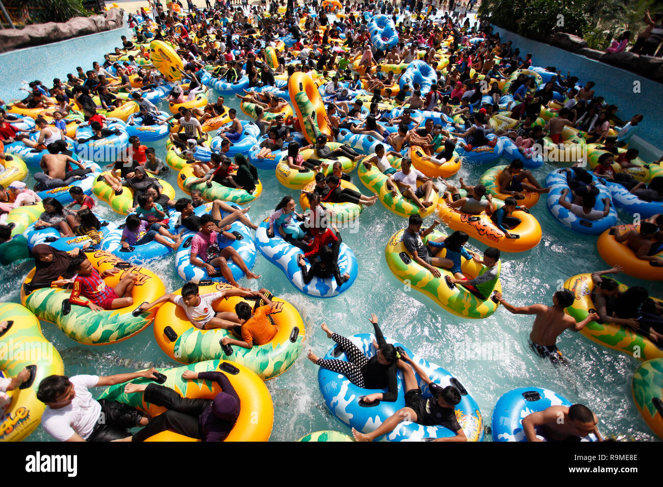 Visitors are seen playing on the waves in the water tourism area of ...