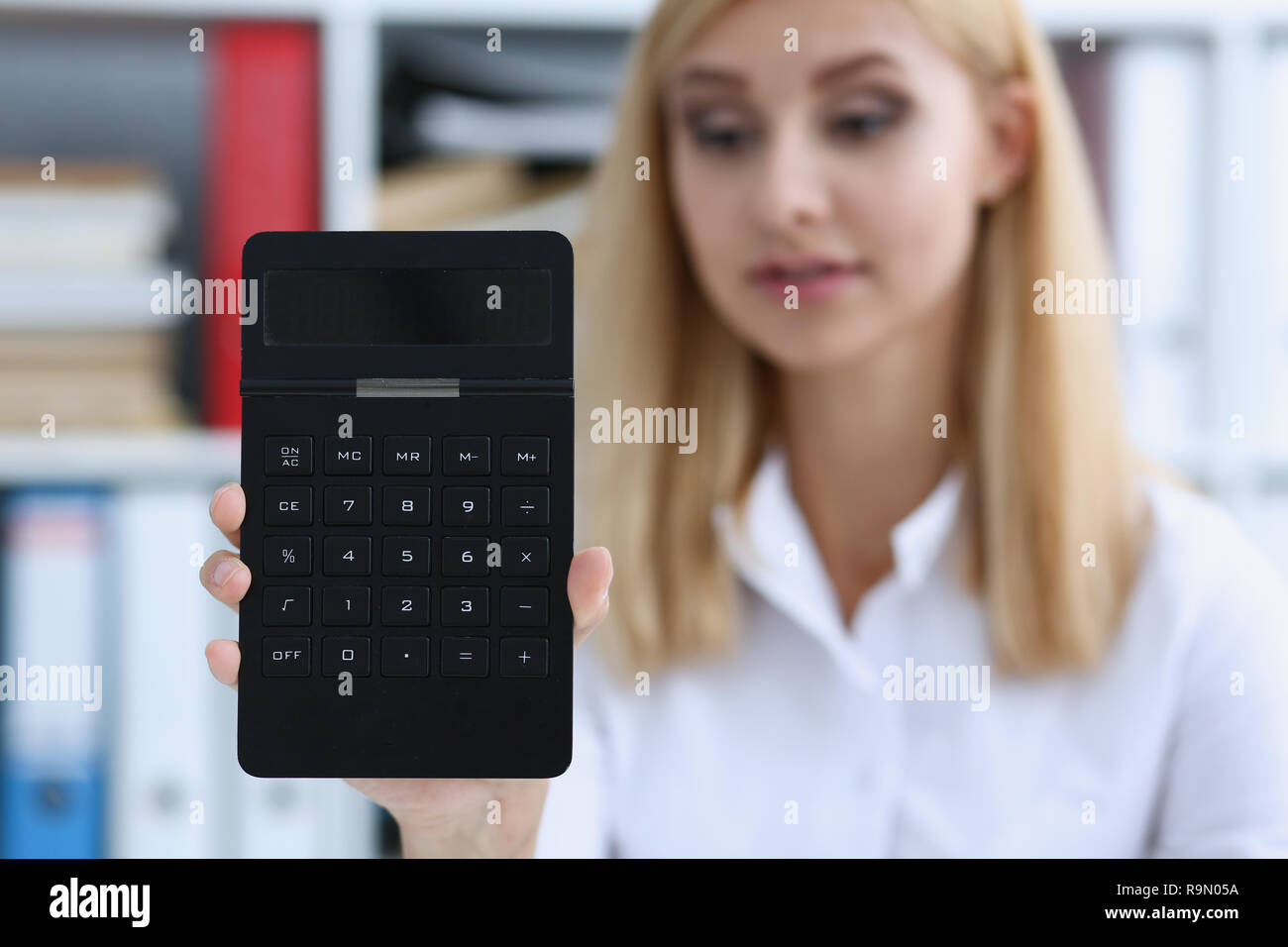 Smiling businesswoman portrait holds calculator in hand Stock Photo - Alamy