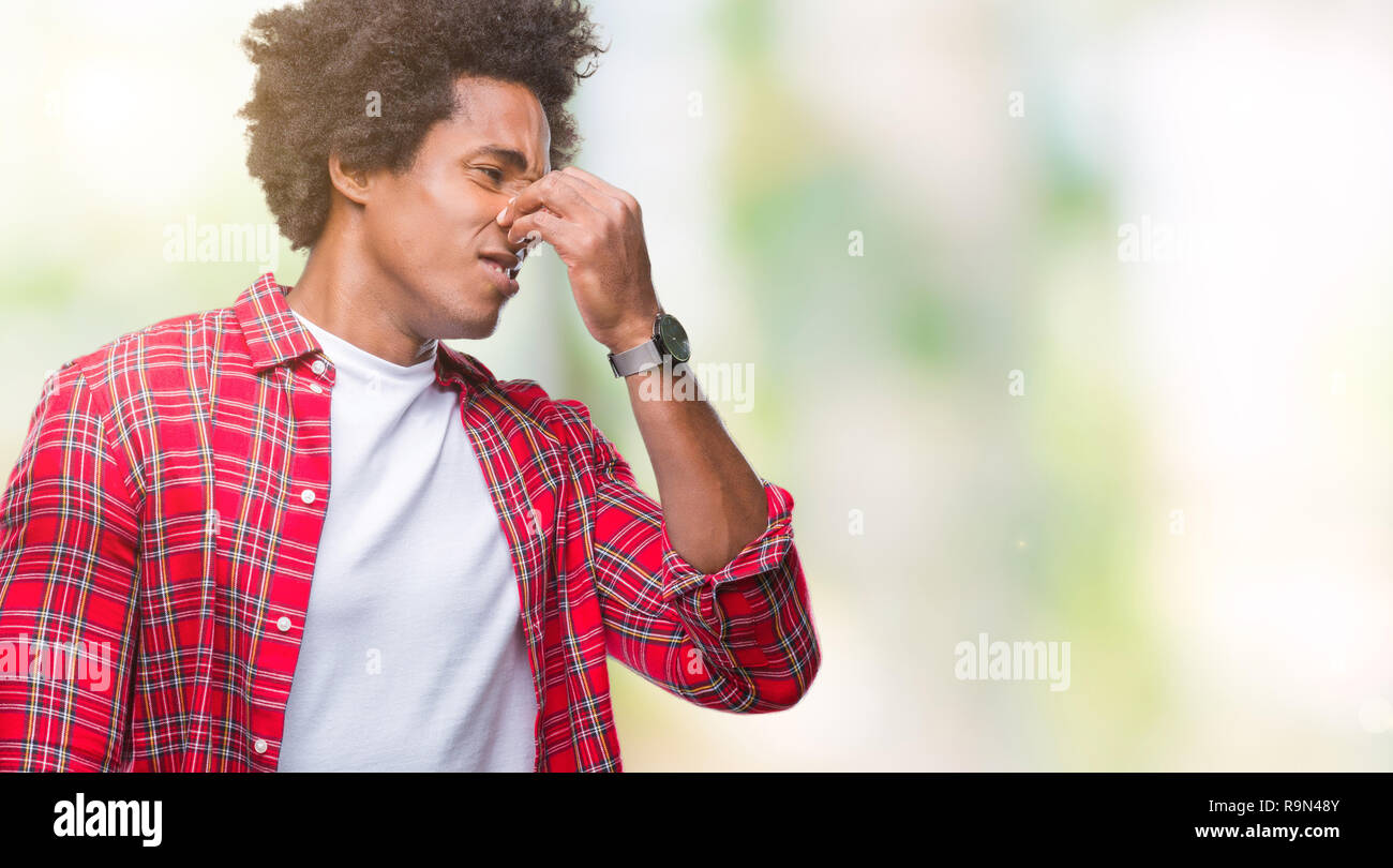 Afro american man over isolated background smelling something stinky ...