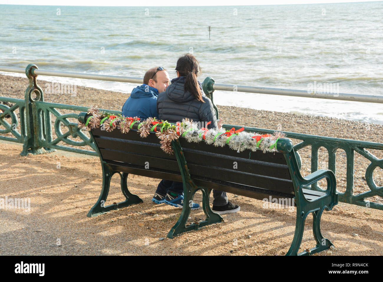 A couple sitting on a bench on Brighton seafront, East Sussex, England ...
