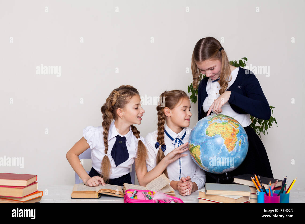 three schoolgirls girls learn world geography lesson on the map Stock ...