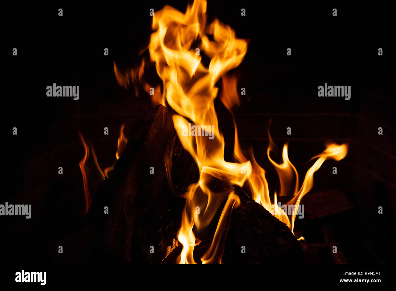 Cozy fireplace. Wood logs burning, dark background, relaxation and warm ...
