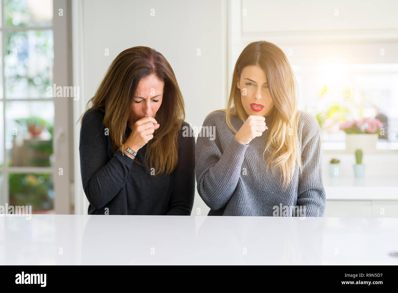 Beautiful family of mother and daughter together at home feeling unwell ...