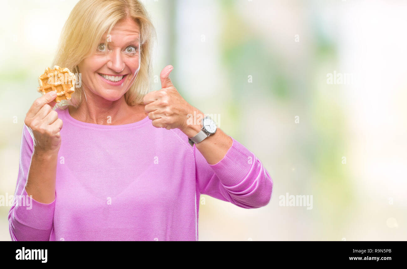 Middle age blonde woman eating sweet waffle over isolated background ...