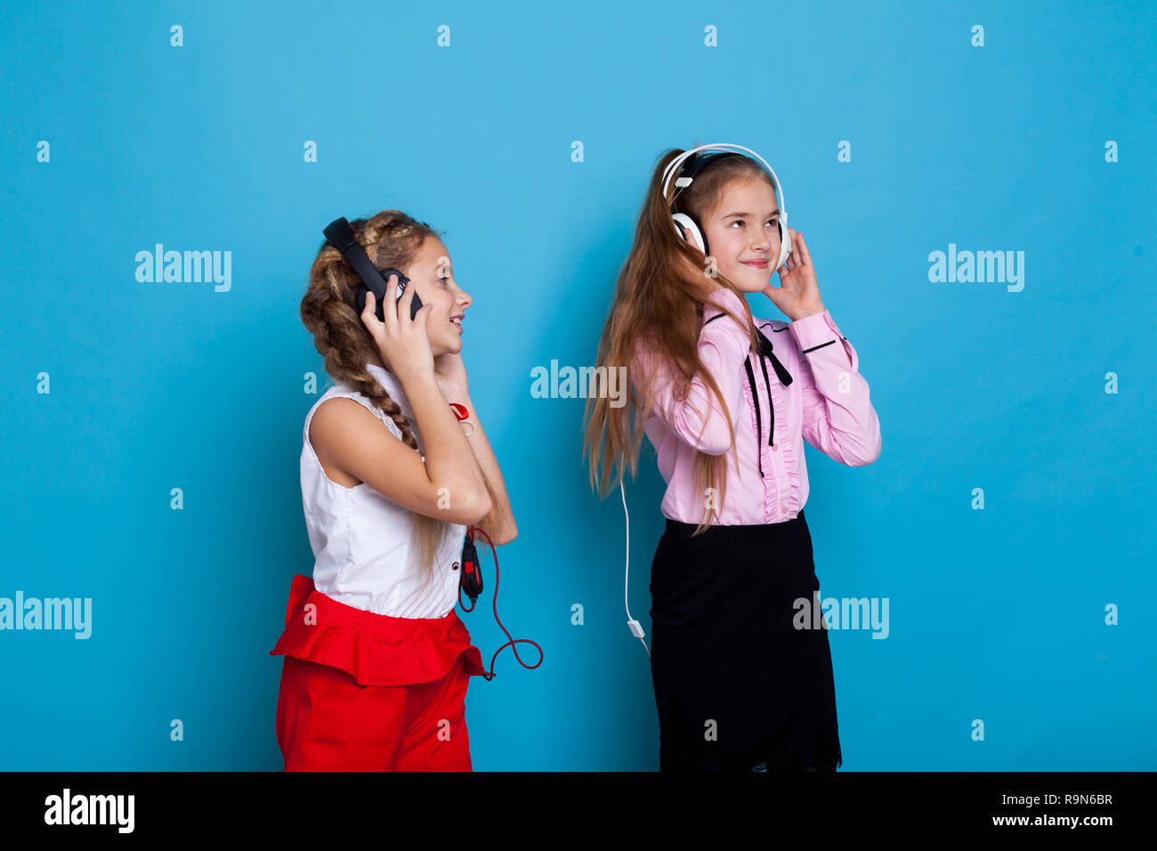 two girls are listening to music with headphones and dance Stock Photo ...