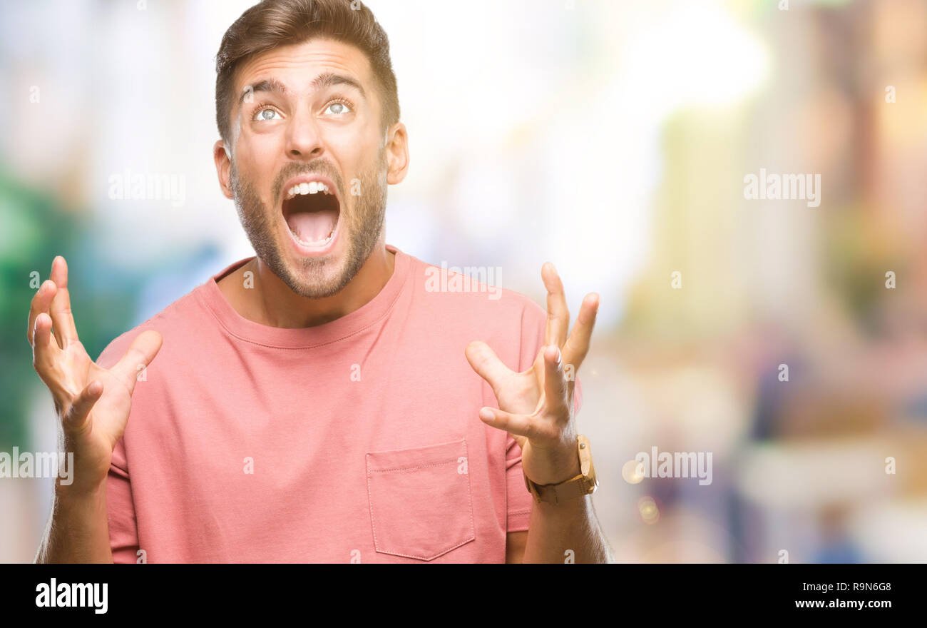 Young handsome man over isolated background crazy and mad shouting and ...