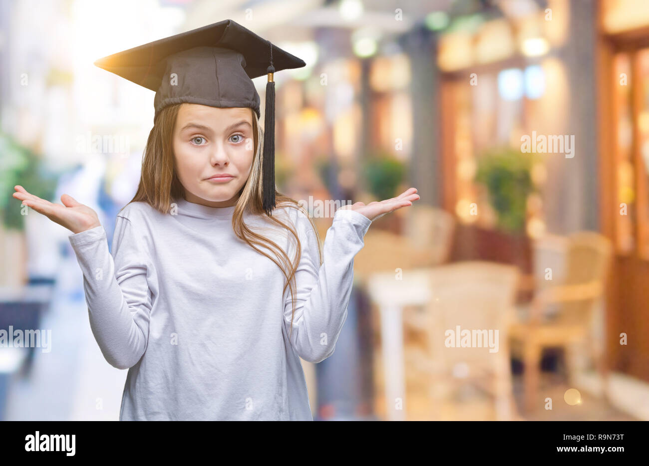 Young beautiful girl wearing graduate cap over isolated background ...