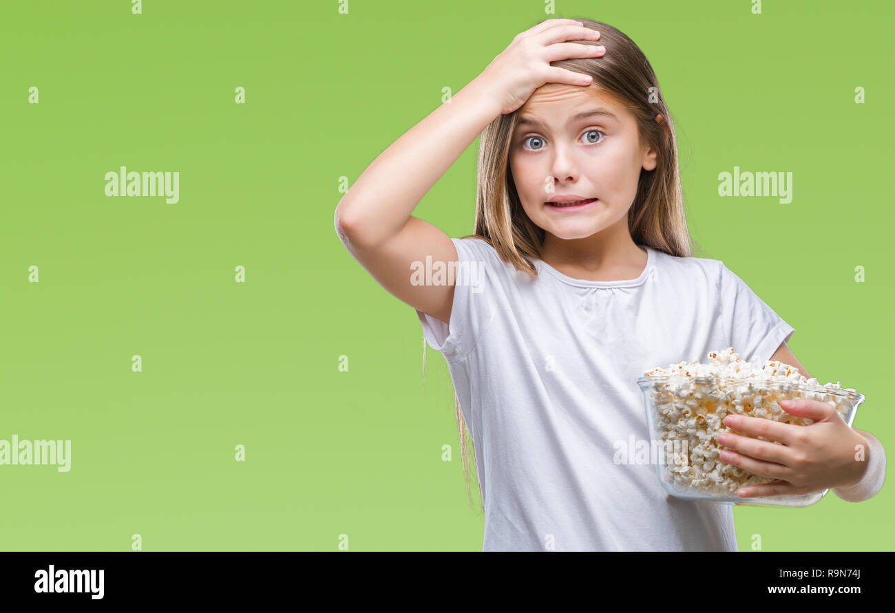 Young beautiful girl eating popcorn snack isolated background stressed ...