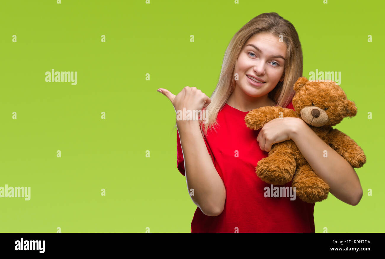 Young caucasian woman holding cute teddy bear over isolated background ...