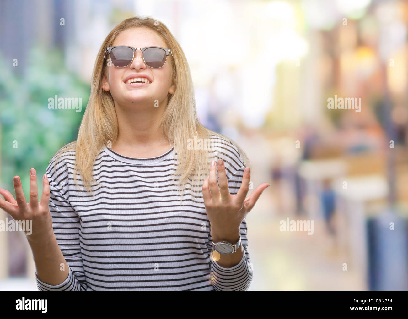 Young caucasian woman wearing sunglasses over isolated background crazy ...