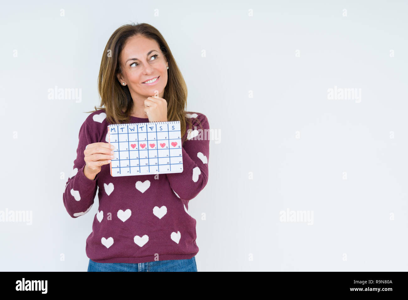 Middle age woman holding menstruation calendar over isolated background ...