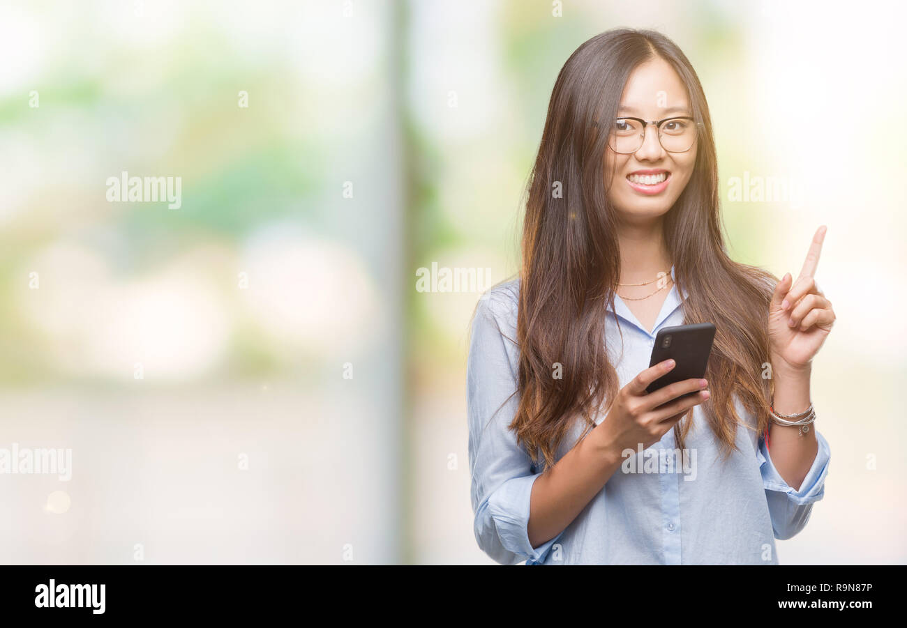 Young asian woman texting using smartphone over isolated background ...