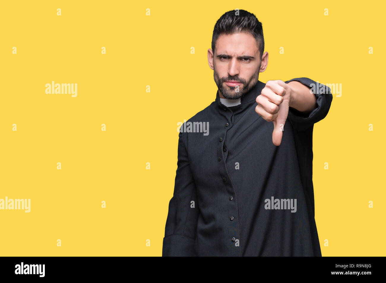 Young Christian priest over isolated background looking unhappy and ...