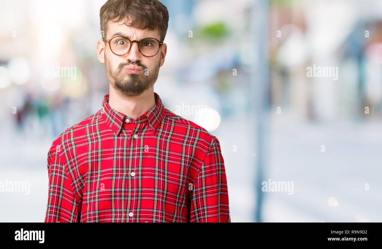 Young handsome man wearing glasses over isolated background puffing ...