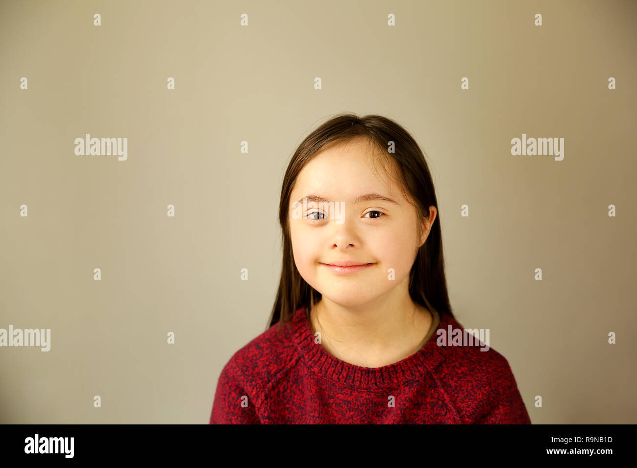 Cute smiling down syndrome girl on the brown background Stock Photo - Alamy