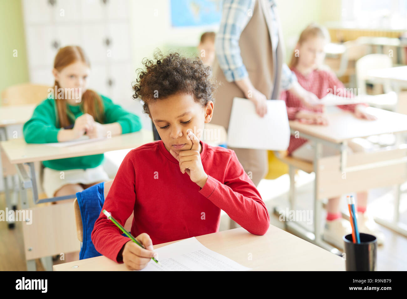 Thoughtful elementary student passing test Stock Photo - Alamy