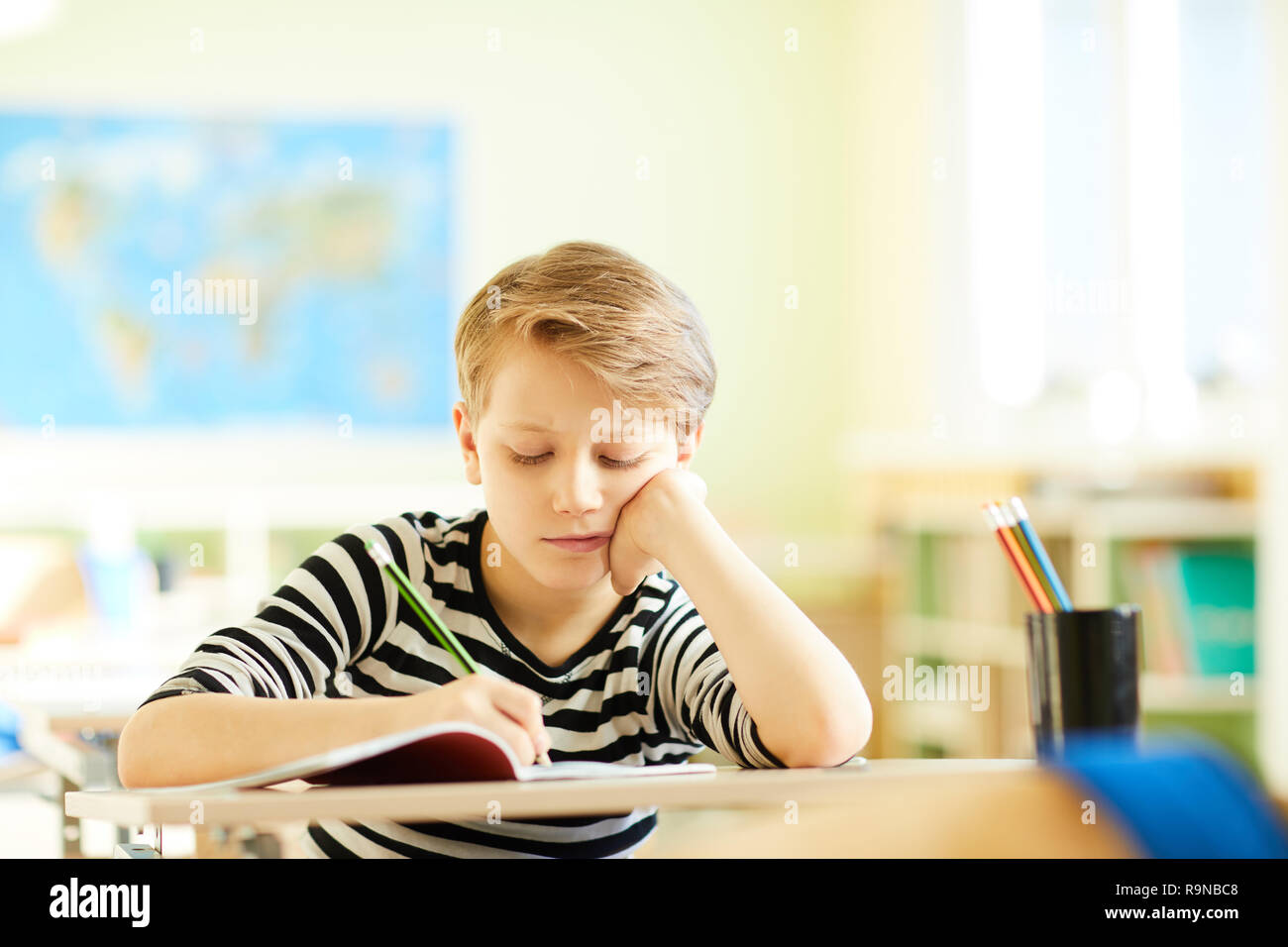 Tired boy drawing in workbook Stock Photo - Alamy