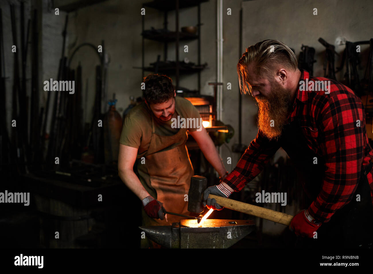 Blacksmiths shaping metal together Stock Photo - Alamy