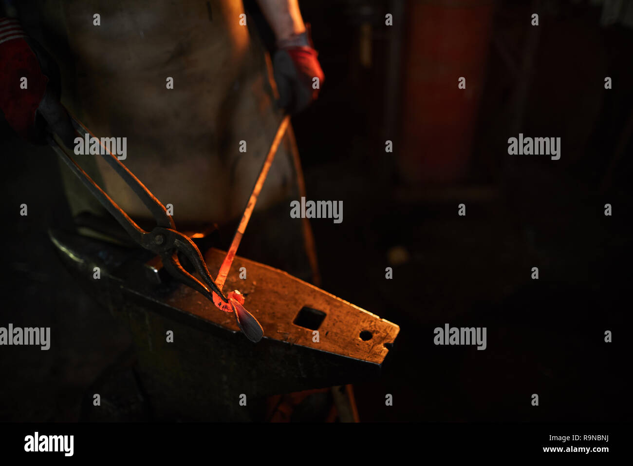 Shaping heated metal plank with tongs Stock Photo - Alamy