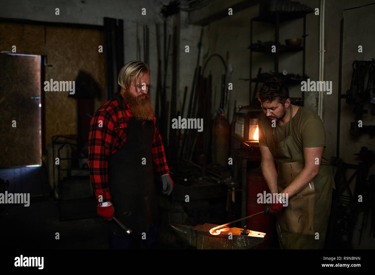 Skilled blacksmith teaching worker Stock Photo - Alamy