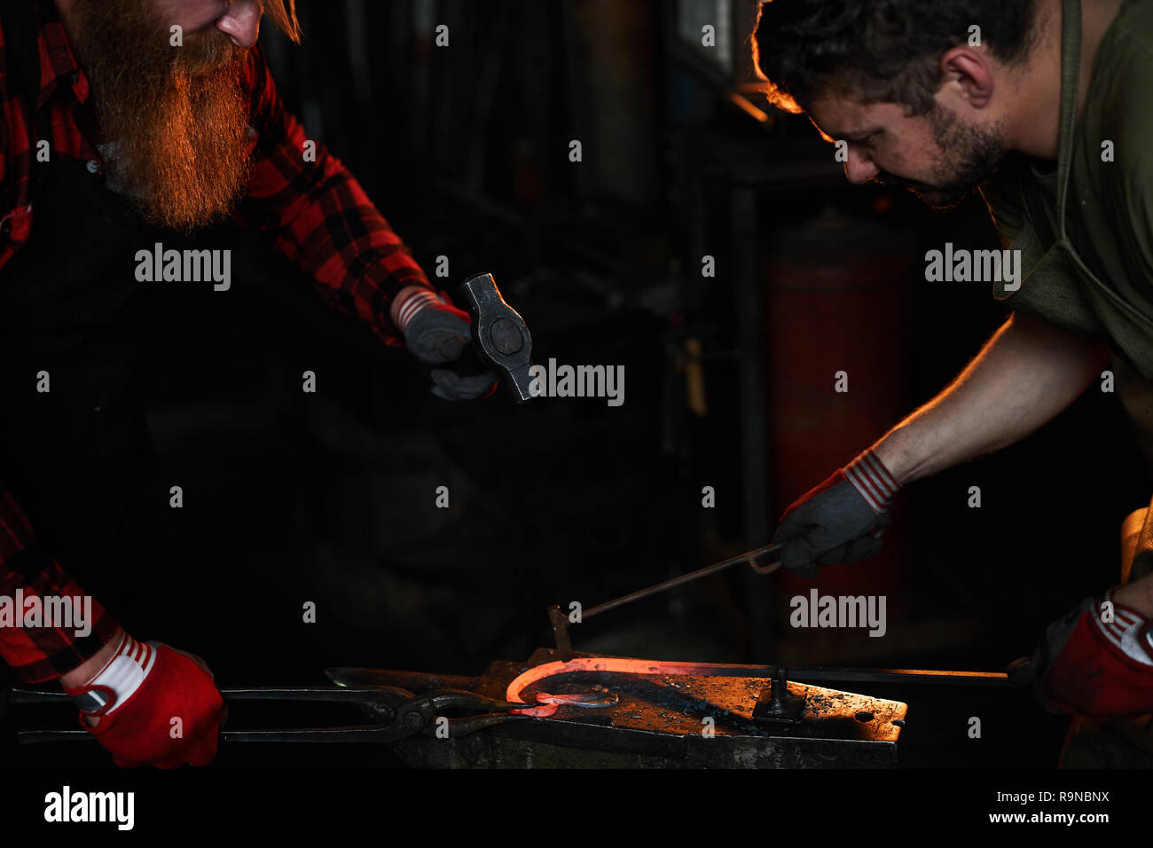 Team of blacksmiths shaping heated metal Stock Photo - Alamy