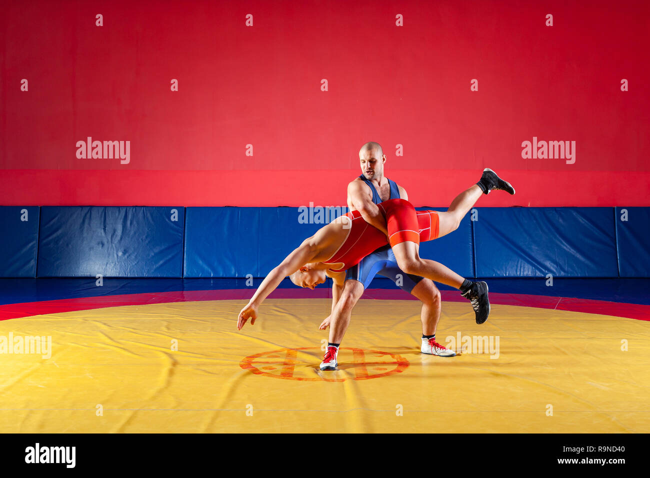 Two greco-roman wrestlers in red and blue uniform making a suplex ...