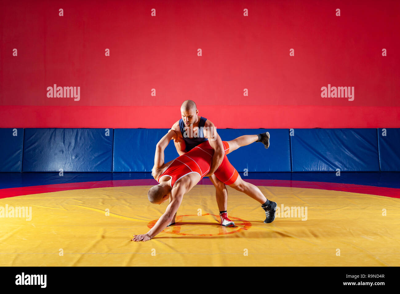 Two greco-roman wrestlers in red and blue uniform making a suplex ...