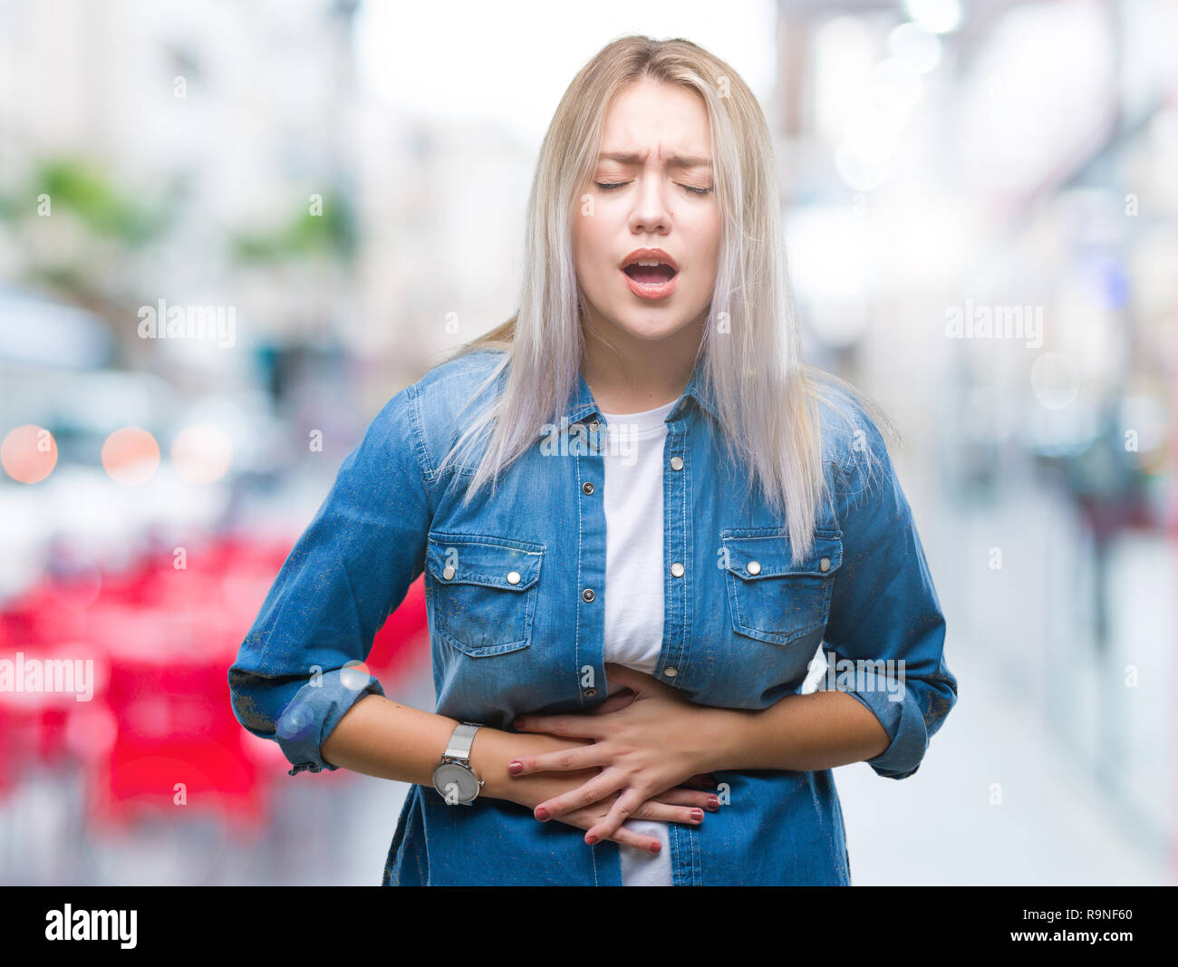 Young blonde woman over isolated background with hand on stomach ...