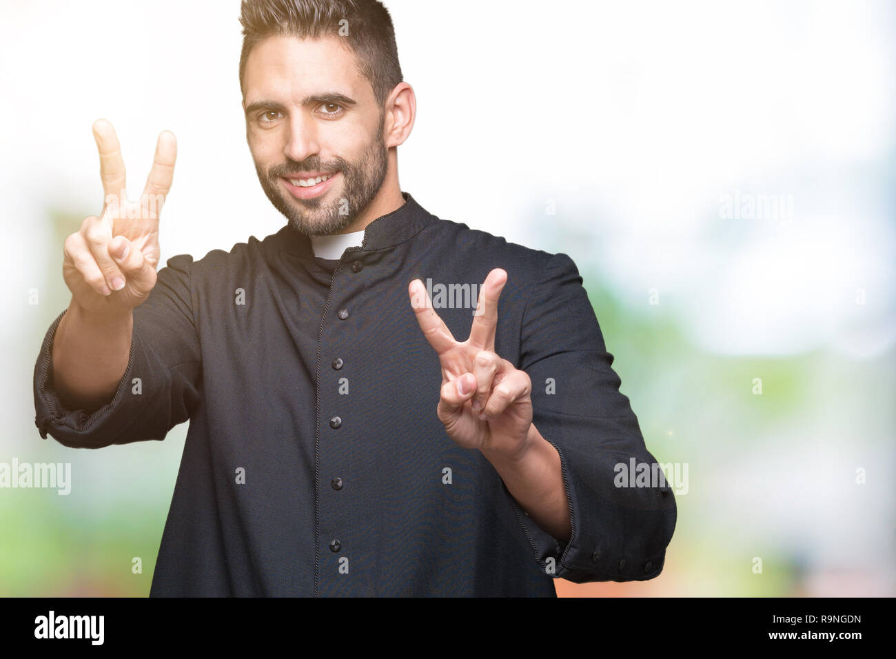 Young Christian priest over isolated background smiling looking to the ...