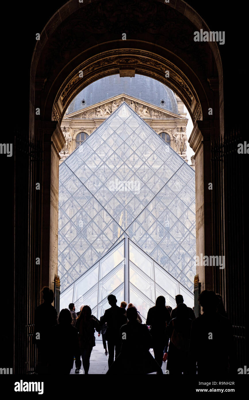 Vertical shot to people entering through the gates of Louvre. Symetric ...