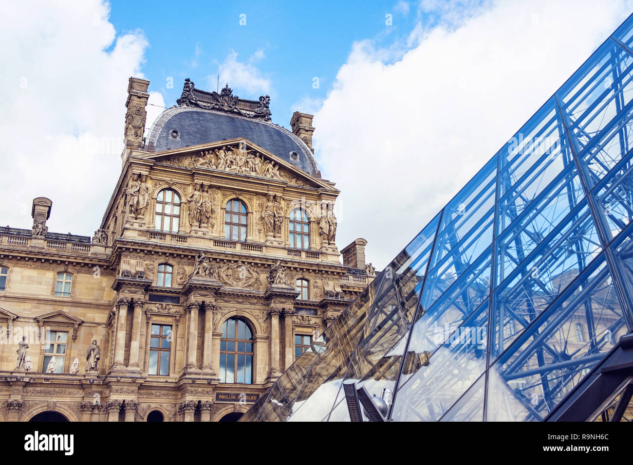 The Museum of Louvre during a cloudy day. The building is reflecting on ...