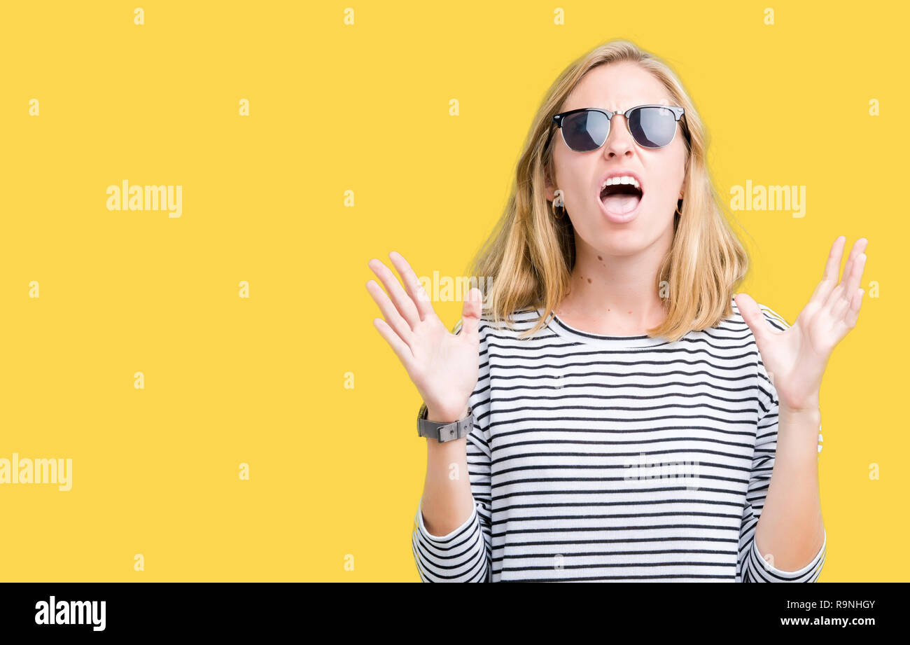 Beautiful young woman wearing sunglasses over isolated background crazy ...