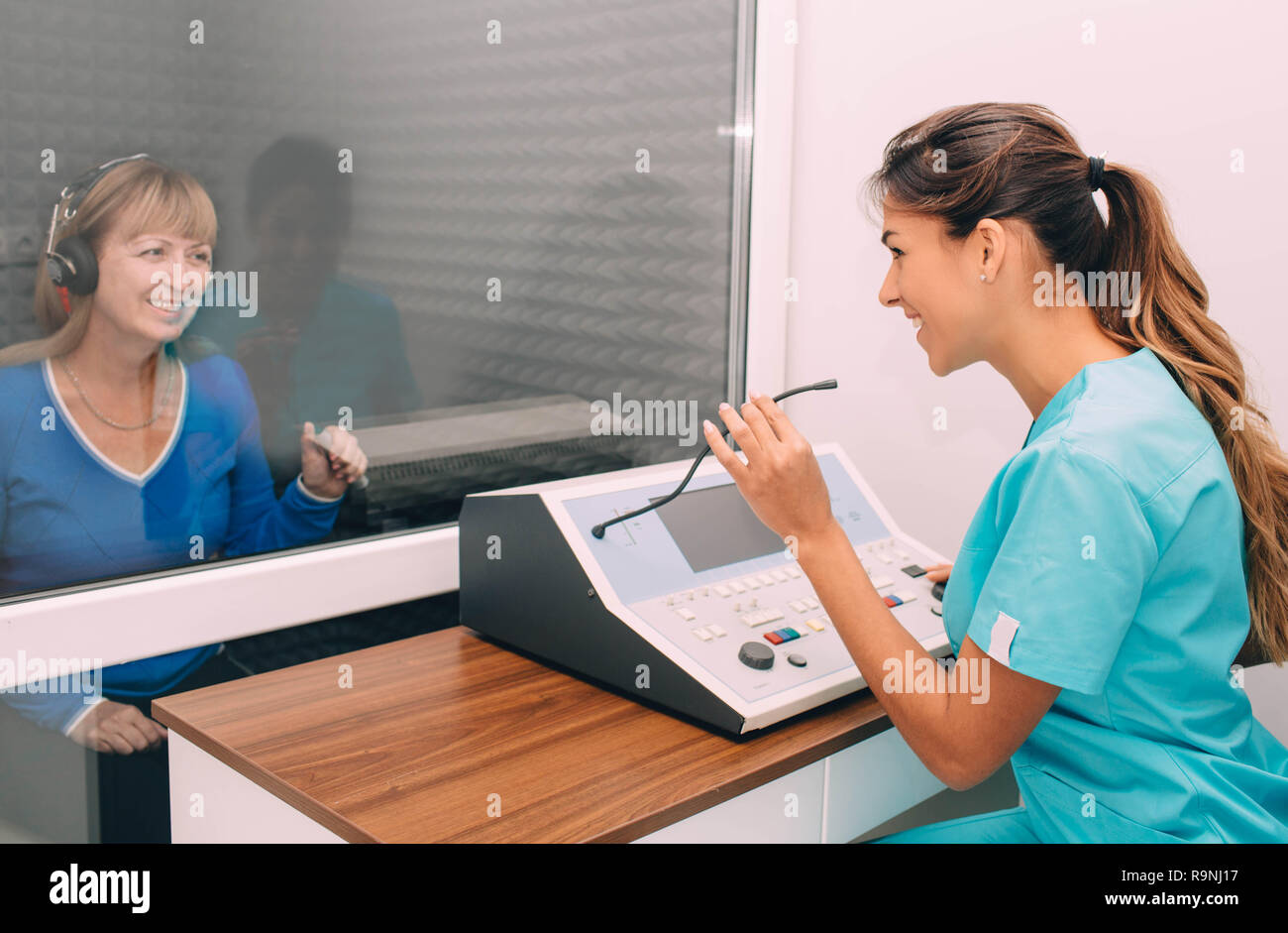 audiologist doing hearing exam to a mature patient using audiometer in ...