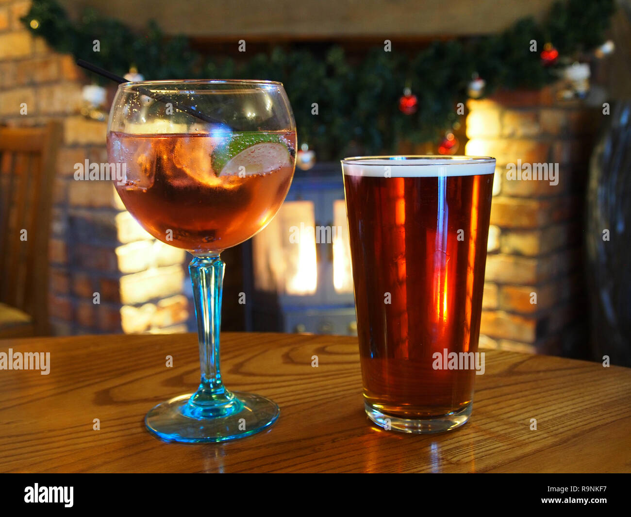 A pint of beer and a cocktail in a cosy English pub in front of the a ...