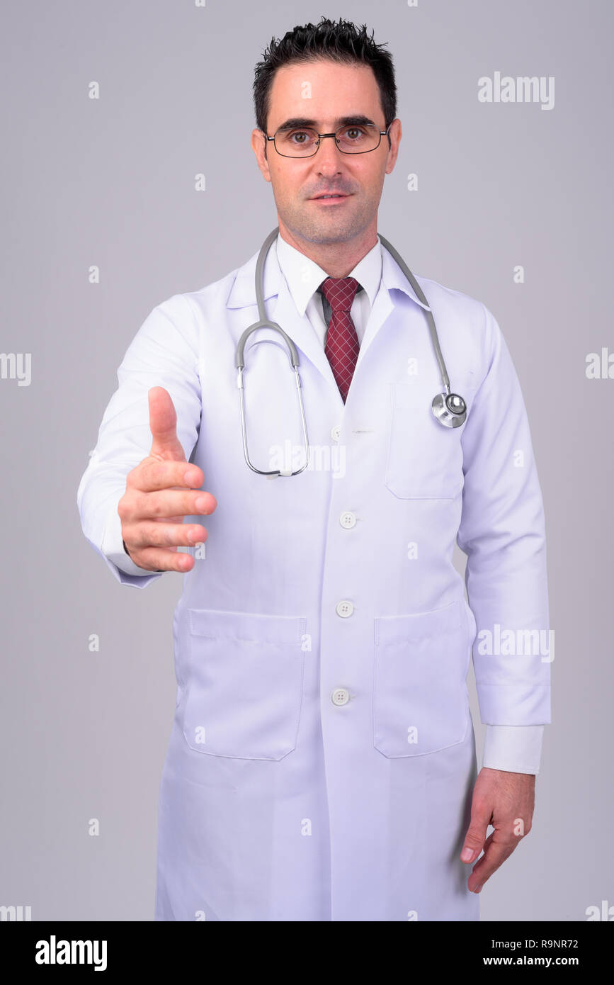 Portrait of handsome man doctor giving handshake against white ...