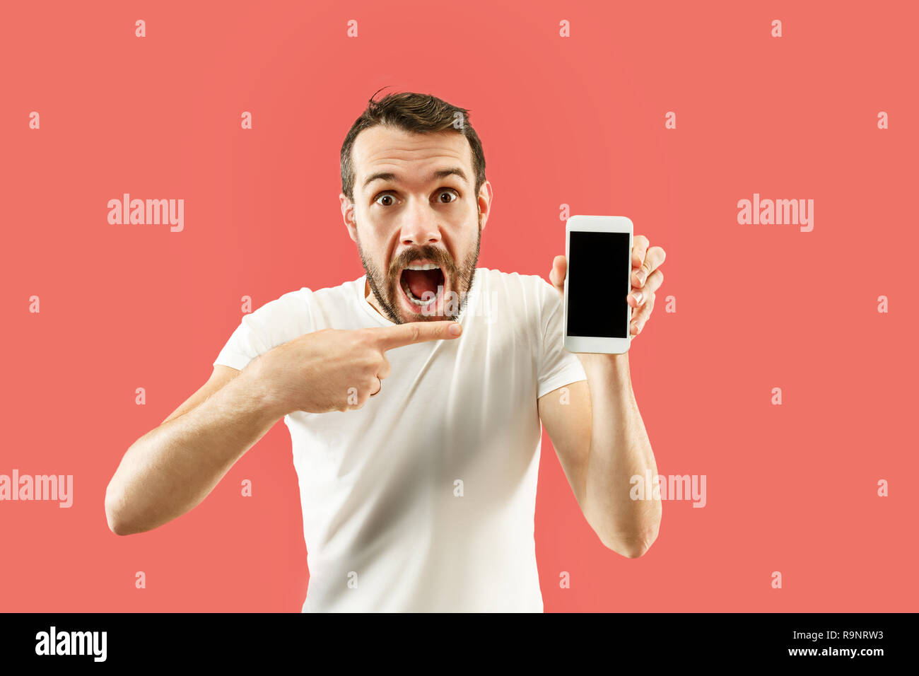 Young handsome man showing smartphone screen over coral background with ...