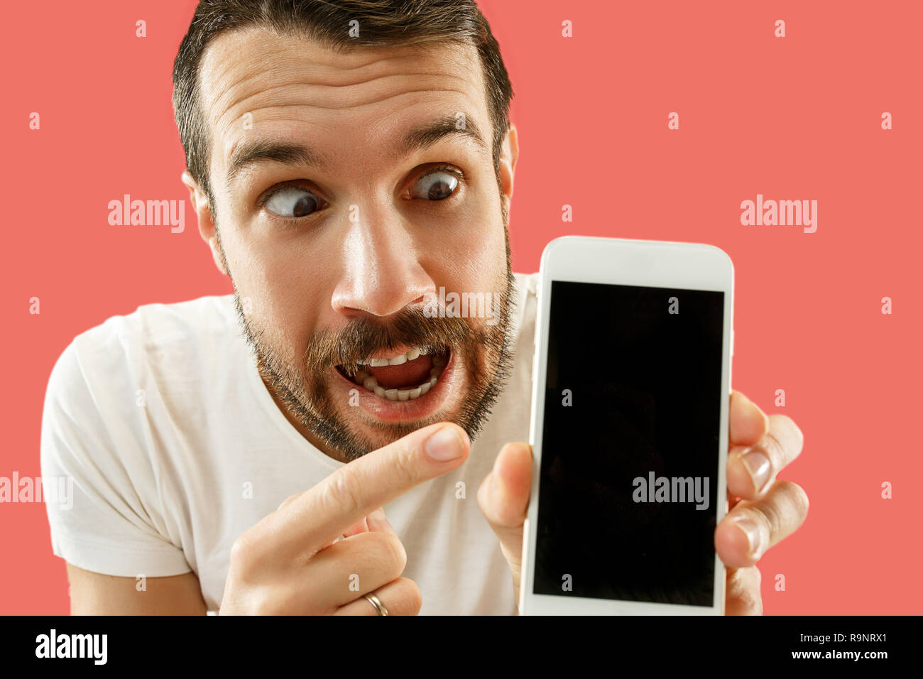 Young handsome man showing smartphone screen over coral background with ...