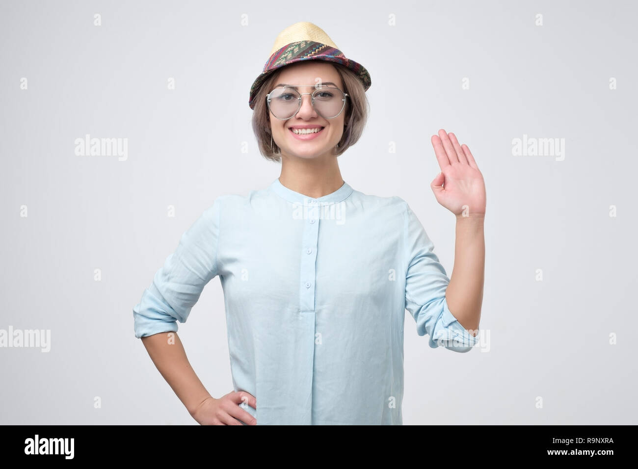 Friendly-looking european teenager dressed in blue shirt saying hello ...